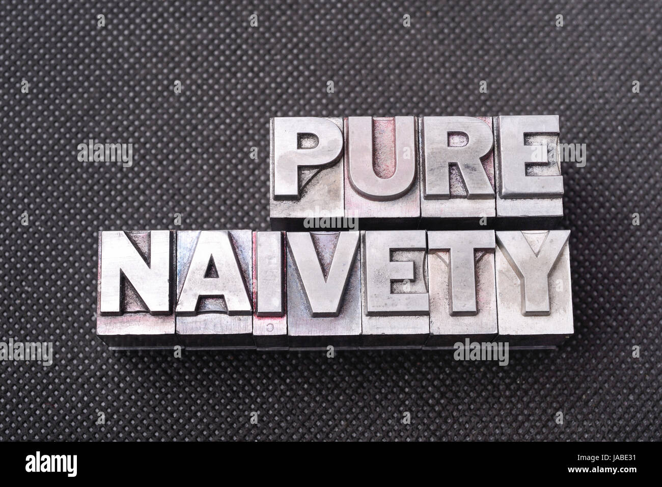 pure naivety phrase made from metallic letterpress blocks on black ...