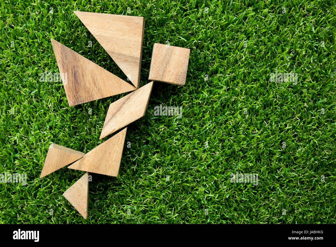 Wooden tangram puzzle in fairy or angel shape on artificial green grass ...