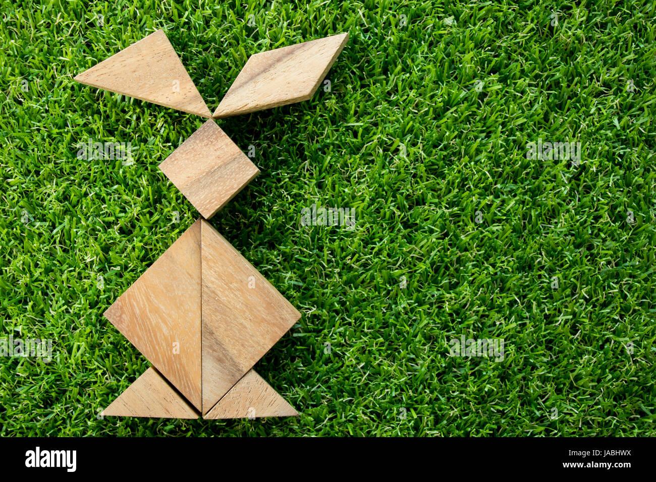 Wooden tangram puzzle in rabbit shape on artificial green grass ...