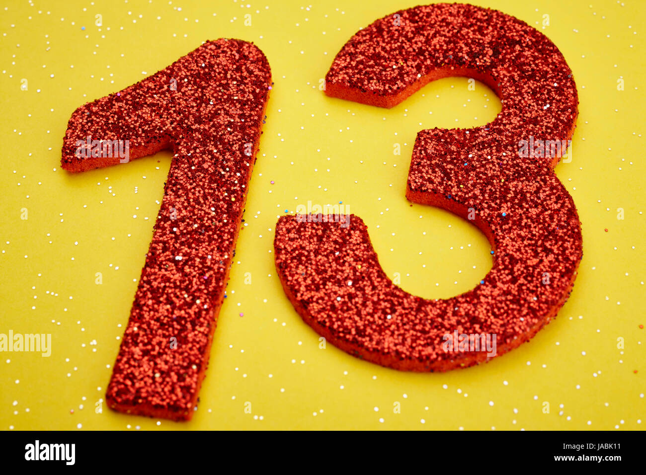 Number thirteen red color over a yellow background. Anniversary ...