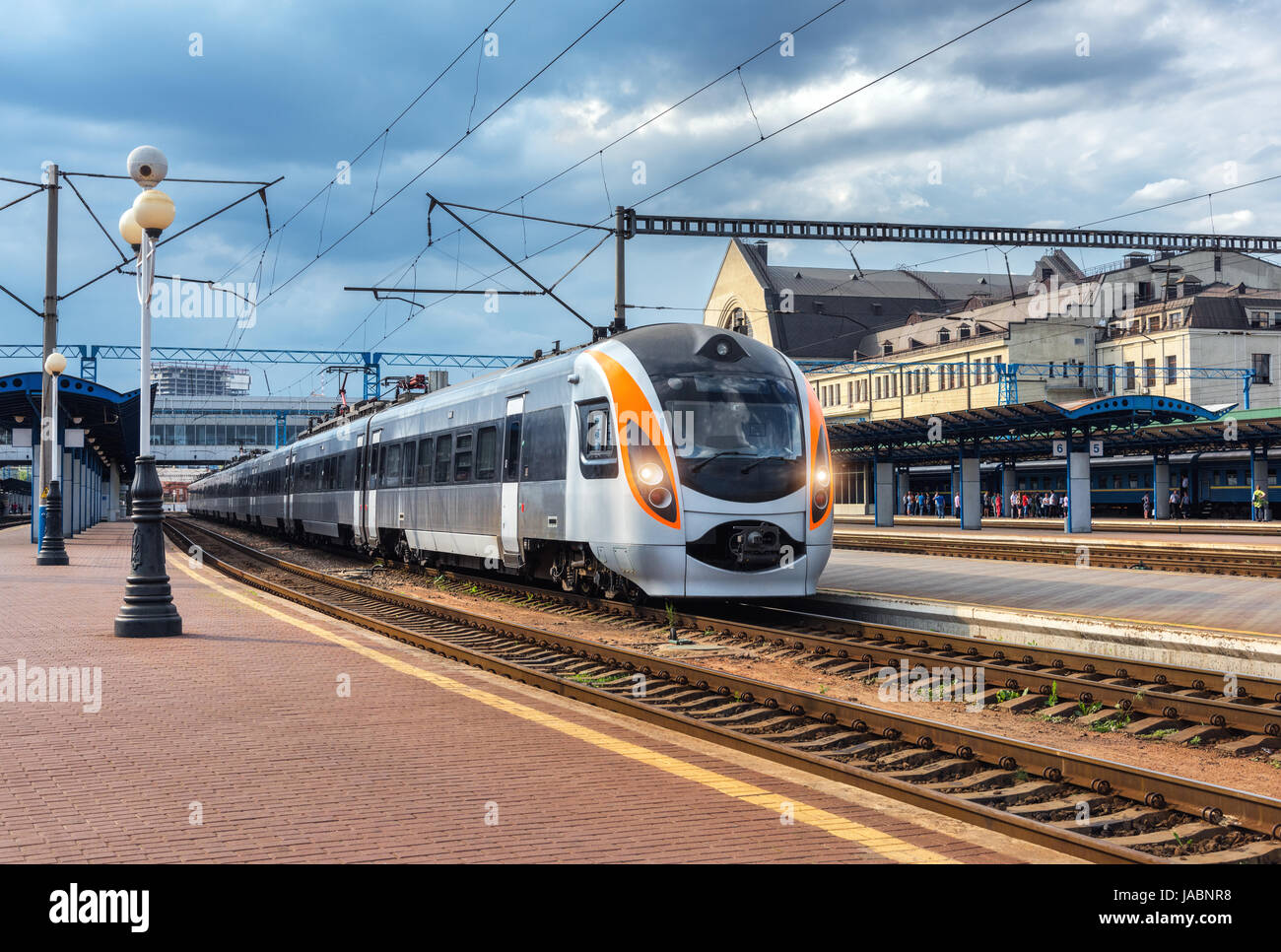 High speed train at the railway station at sunset in Europe. Modern ...