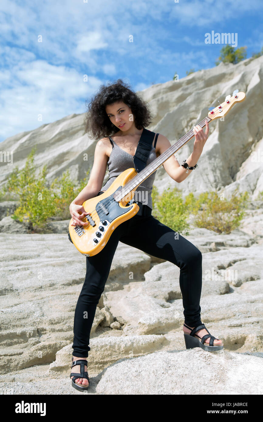 Woman play yellow bass guitar on sandy background Stock Photo - Alamy