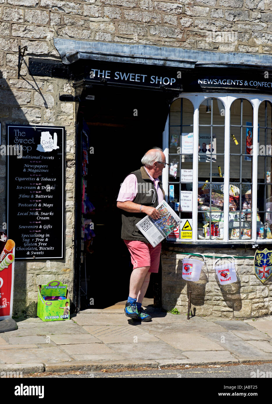 Man leaving sweet shop in the village of Corfe Castle, Dorset, England ...