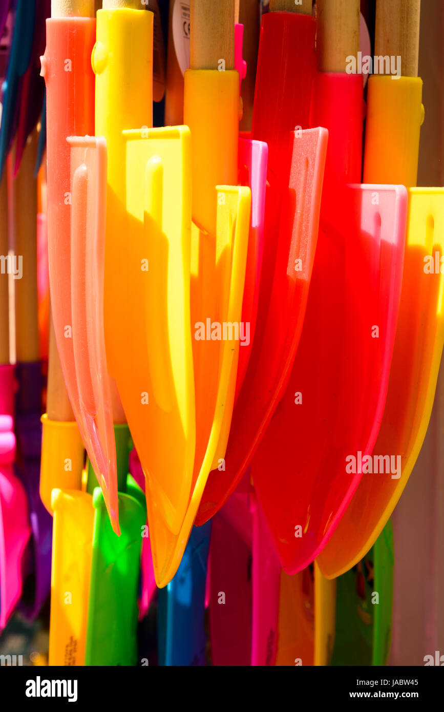 Selection of colourful plastic spades outside shop front. Tenby ...