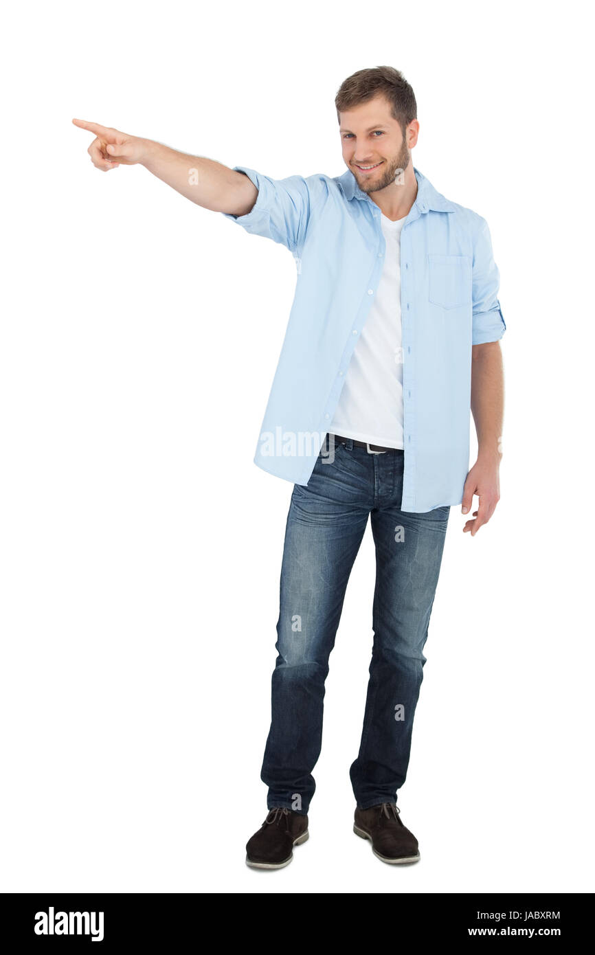 Confident model looking at camera while pointing on white background ...