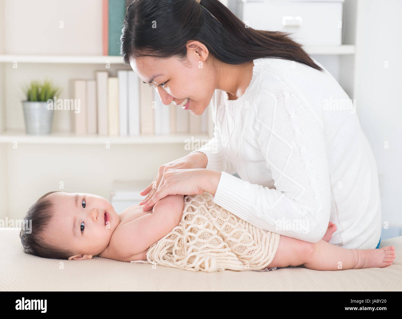 Asian mother giving massage to baby girl at home Stock Photo - Alamy