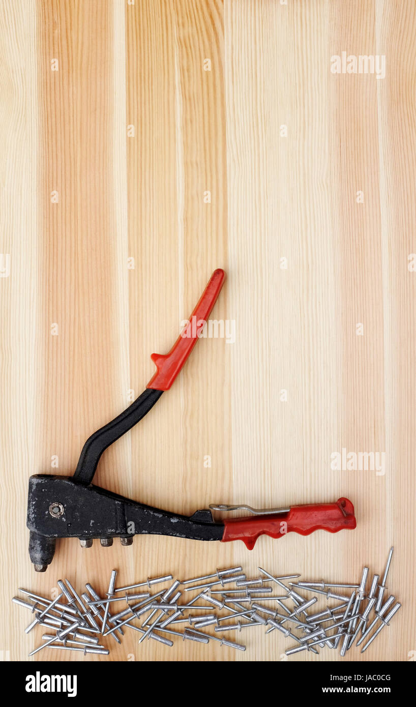 Metal pop rivets and a riveter on wood as DIY themed background Stock ...