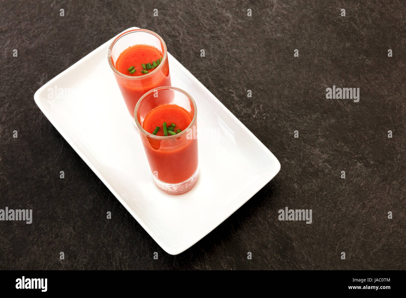 Spanish tapas in a modern bar. Two shots of gazpacho, cold tomato soup ...