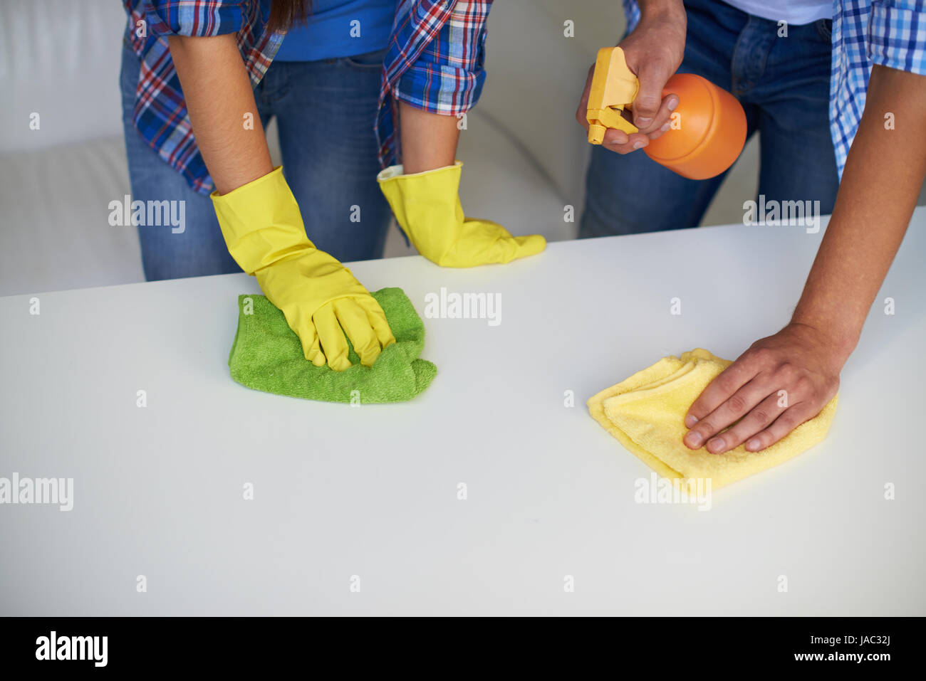 Close-up of female and male hands cleaning table surface with dusters ...