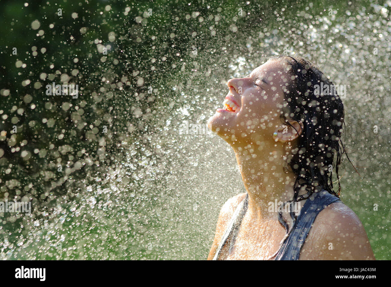 Beautiful woman enjoying under a water jet with thousands of drops in ...