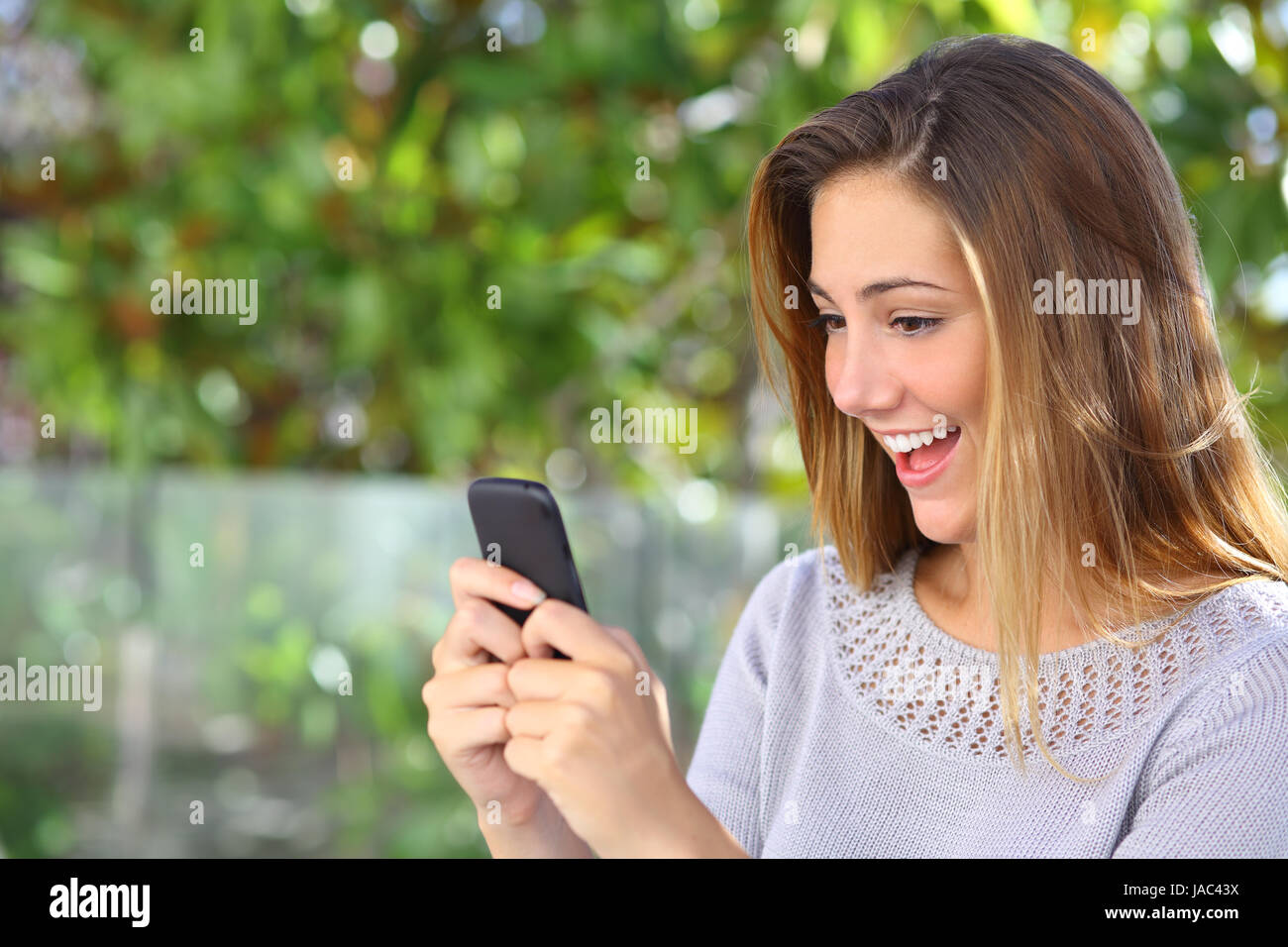 Beautiful woman browsing internet happy in her smart phone with a green ...