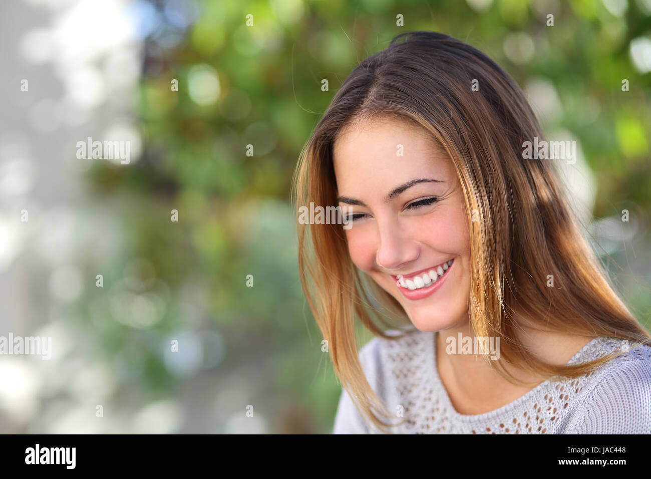 Beautiful woman laughing happy outdoor with a green unfocused ...