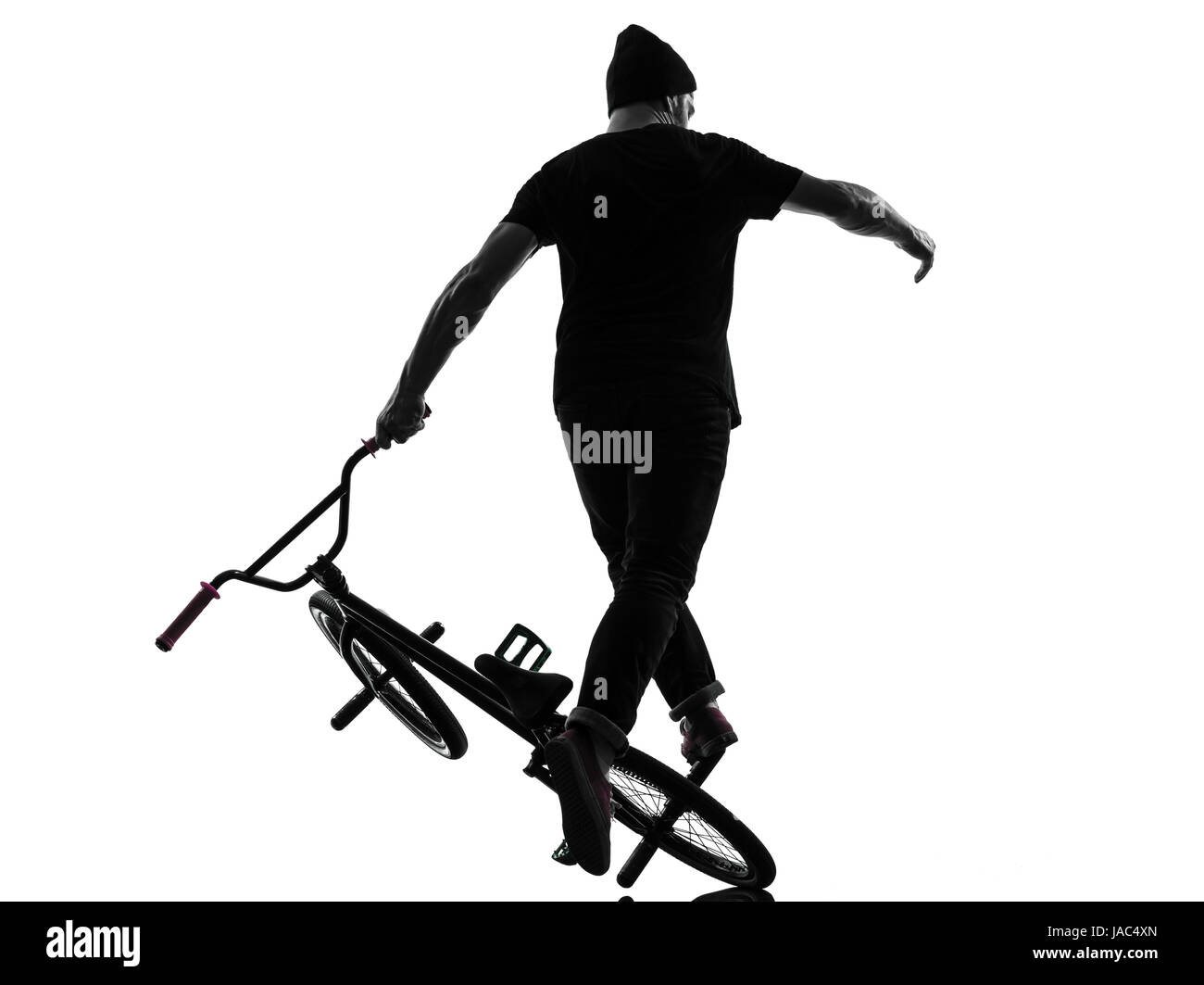 one caucasian man exercising bmx acrobatic figure in silhouette studio ...