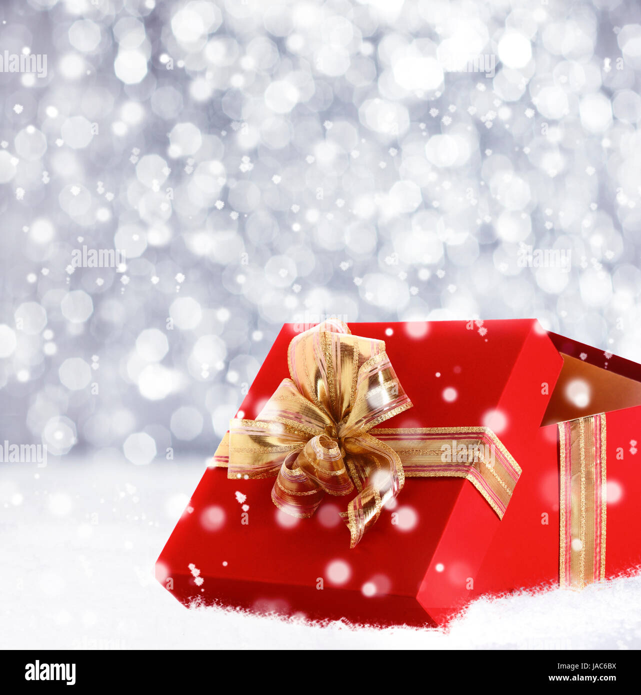 Red Christmas gift box with its lid propped at an angle in front to ...