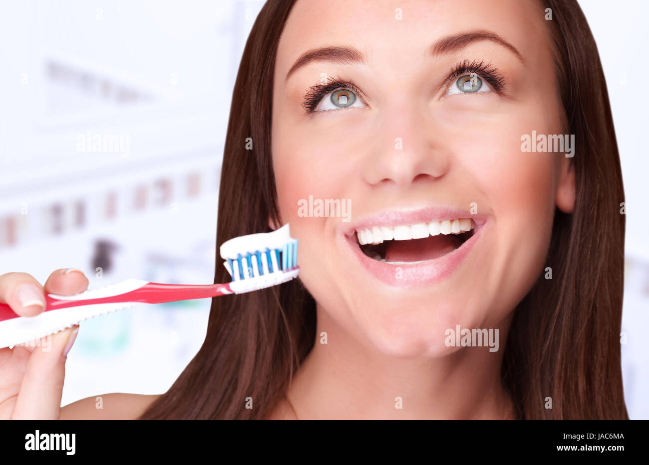 Closeup portrait of beautiful woman clean teeth in the bathroom at home ...