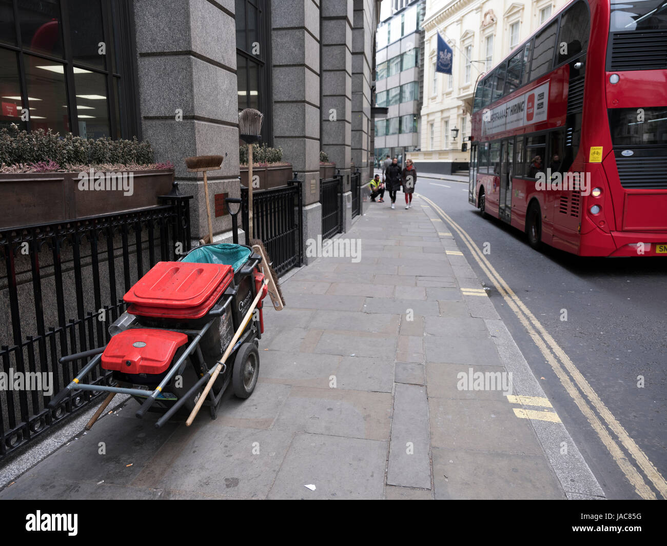 cleaner's cart with brooms on pavement in the city of london while bus ...