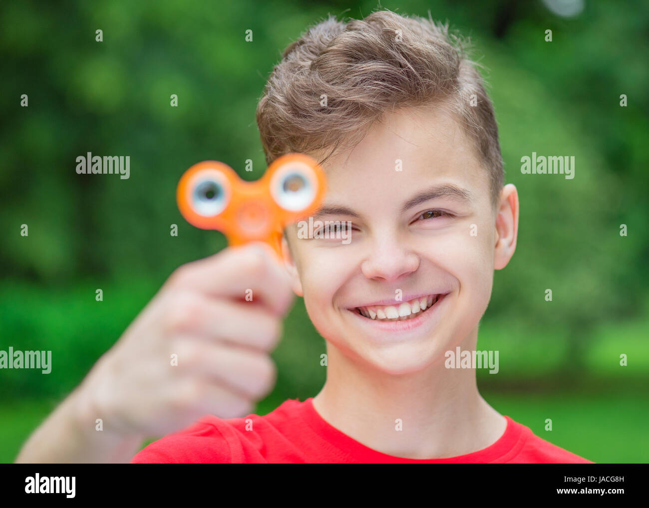 Teen boy with spinner toy in park Stock Photo - Alamy