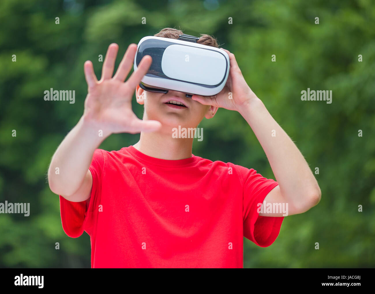 Teen boy with VR glasses in park Stock Photo - Alamy
