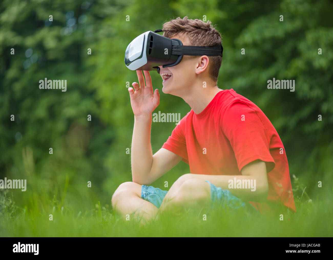 Teen boy with VR glasses in park Stock Photo - Alamy