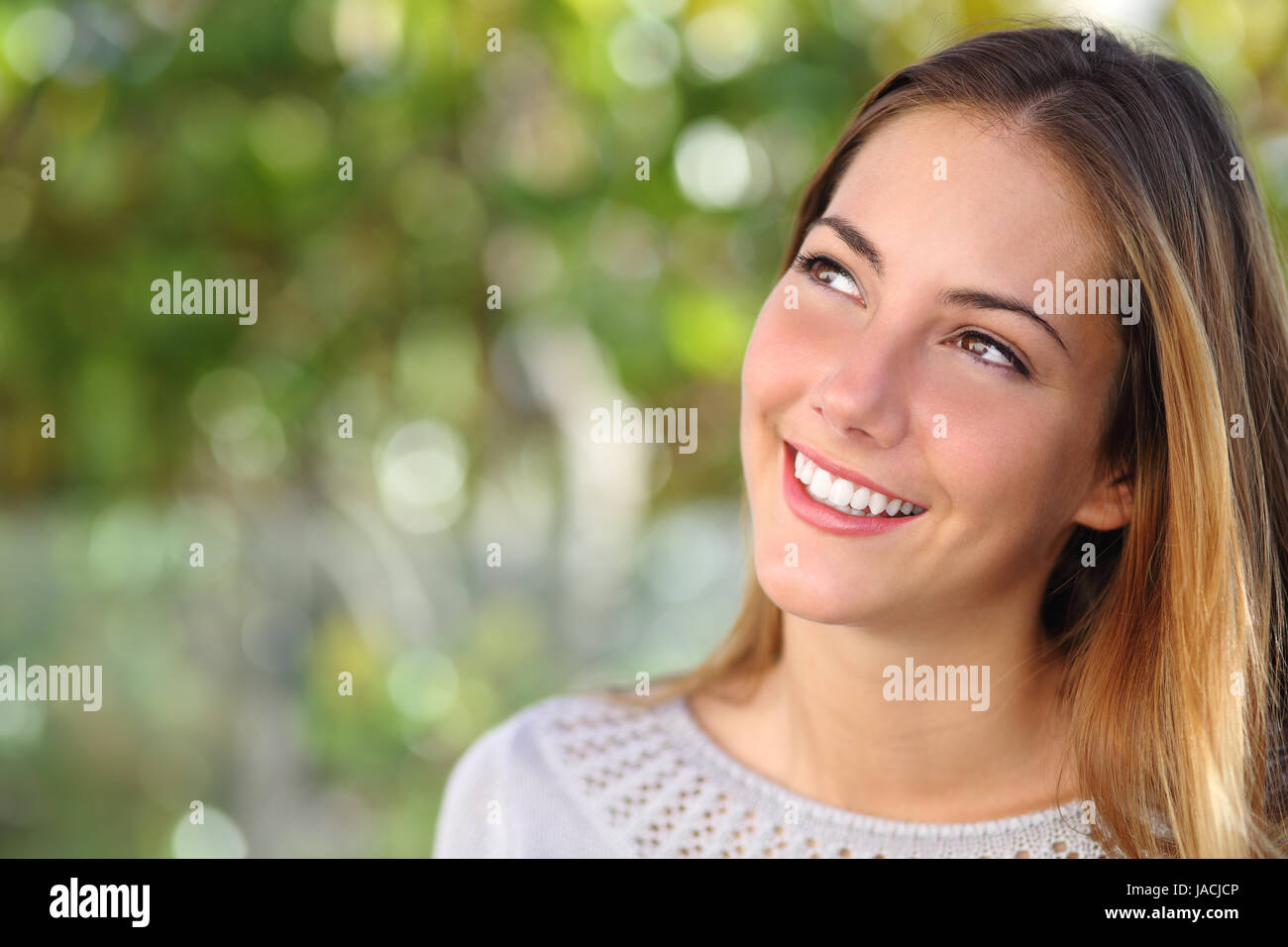 Beautiful woman smiling with a perfect teeth and looking above with a ...