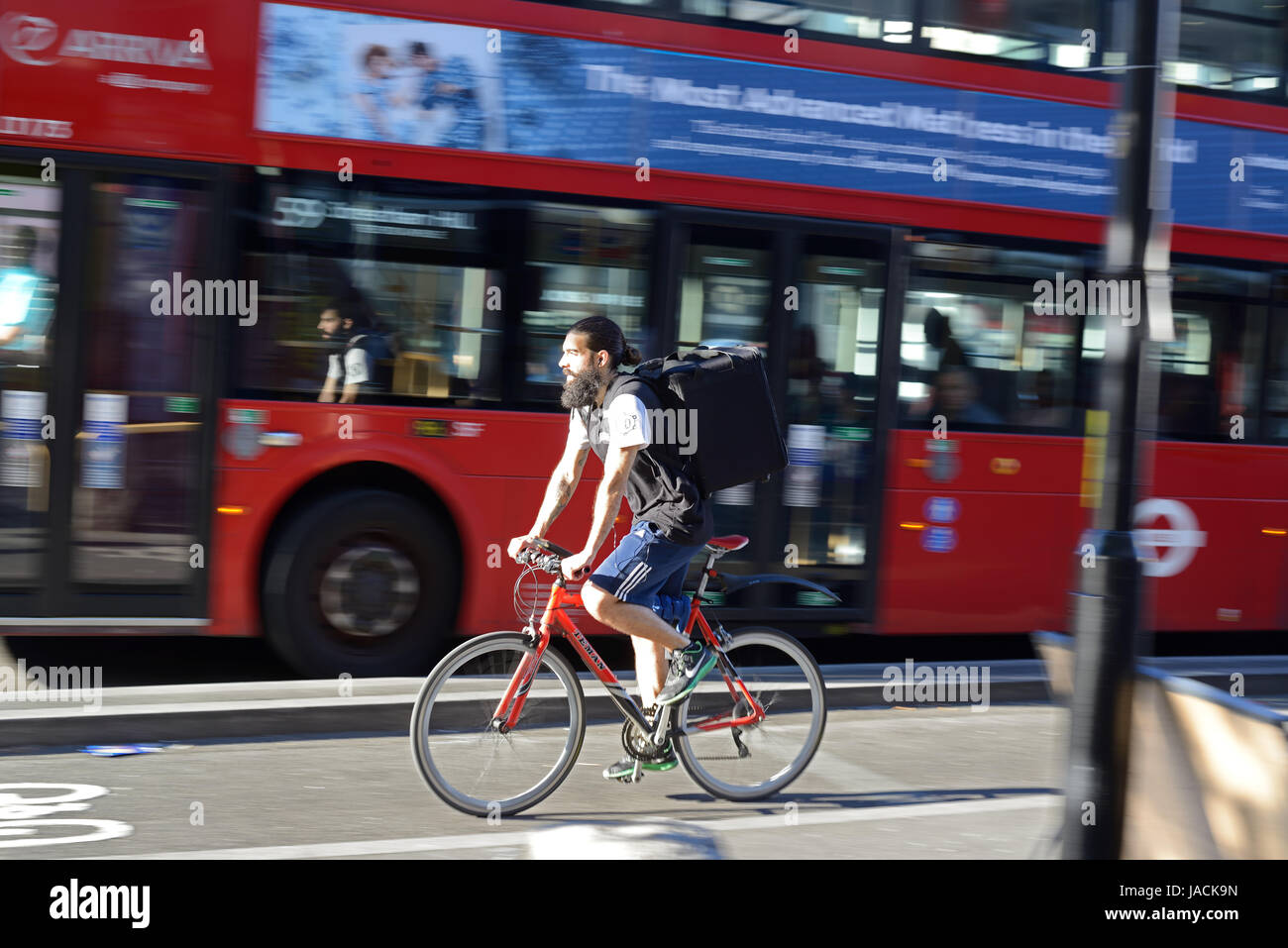 Uber food delivery cyclist cycling through Kings Cross, London, in the ...