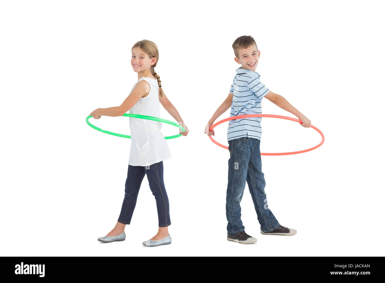 Brother and sister playing with hula hoop together on white background ...