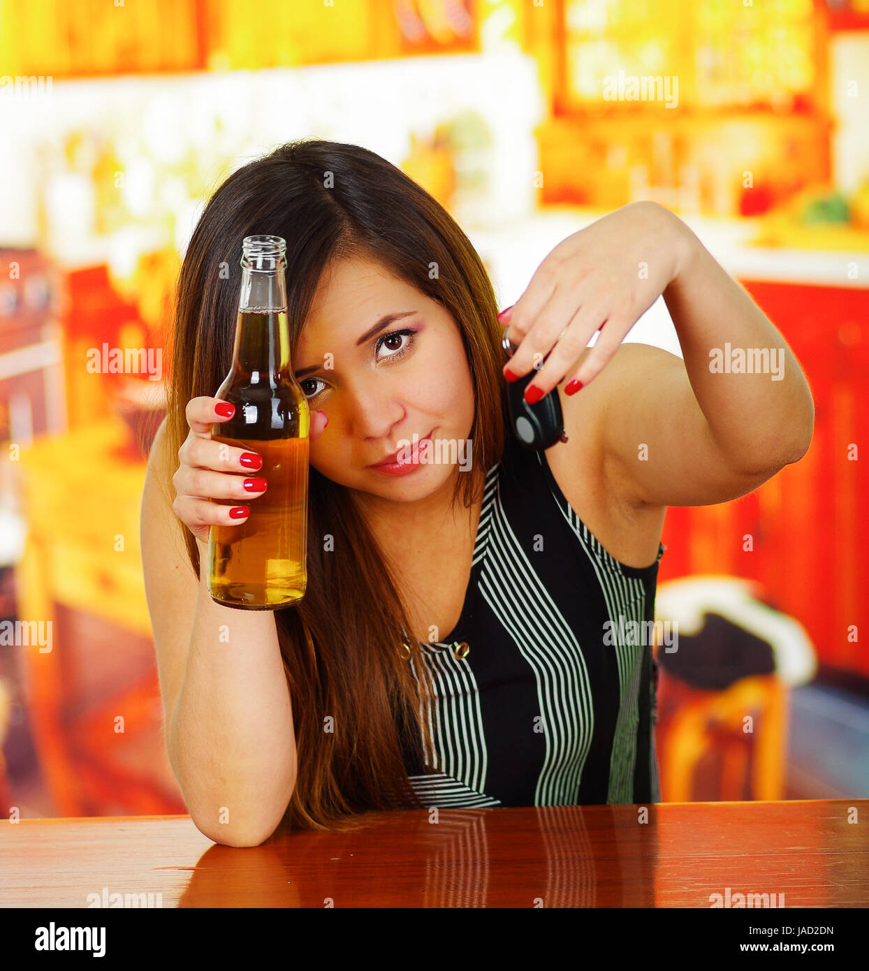 Portrait of a beautiful woman holding a beer with one hand and her car ...