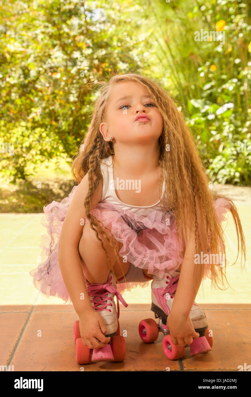 Little girl preschool crouching on ground wearing her roller skates, in ...