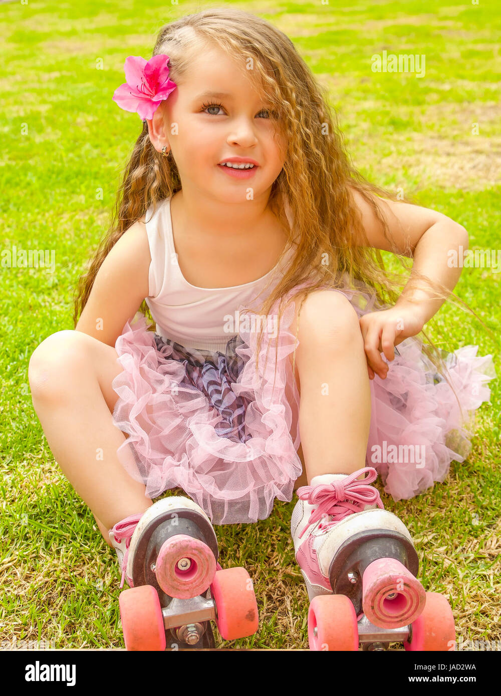 Little girl preschool beginner in roller skates, in a grass background ...