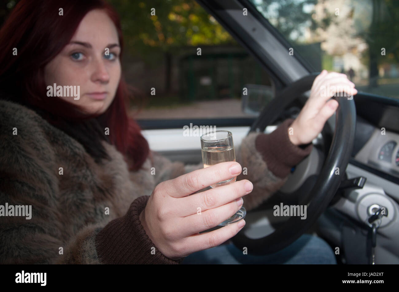 Drunk woman driving car with vodka in hand Stock Photo - Alamy