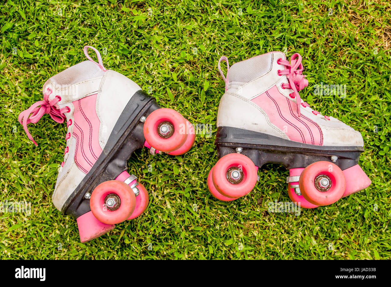 Beautiful pink roller skates on grass background Stock Photo - Alamy