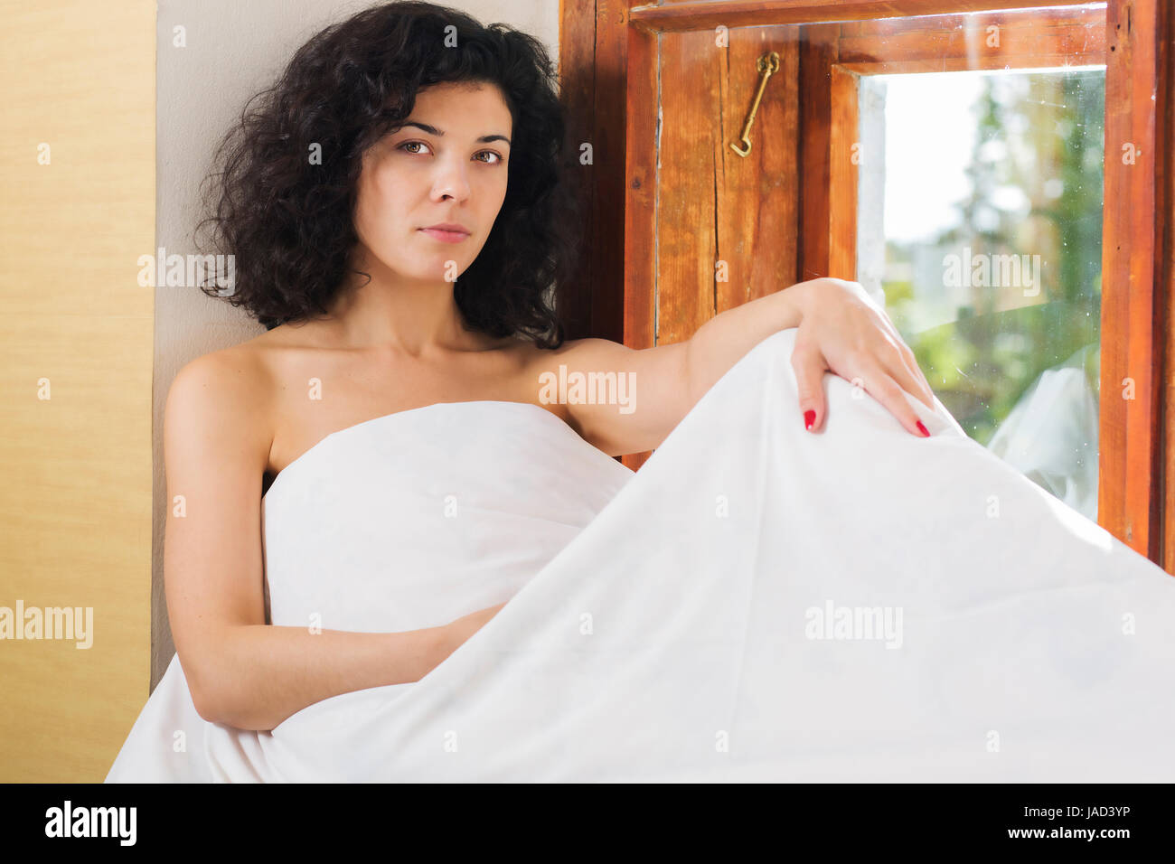 Pretty woman sit near window covered by bed blanket Stock Photo - Alamy
