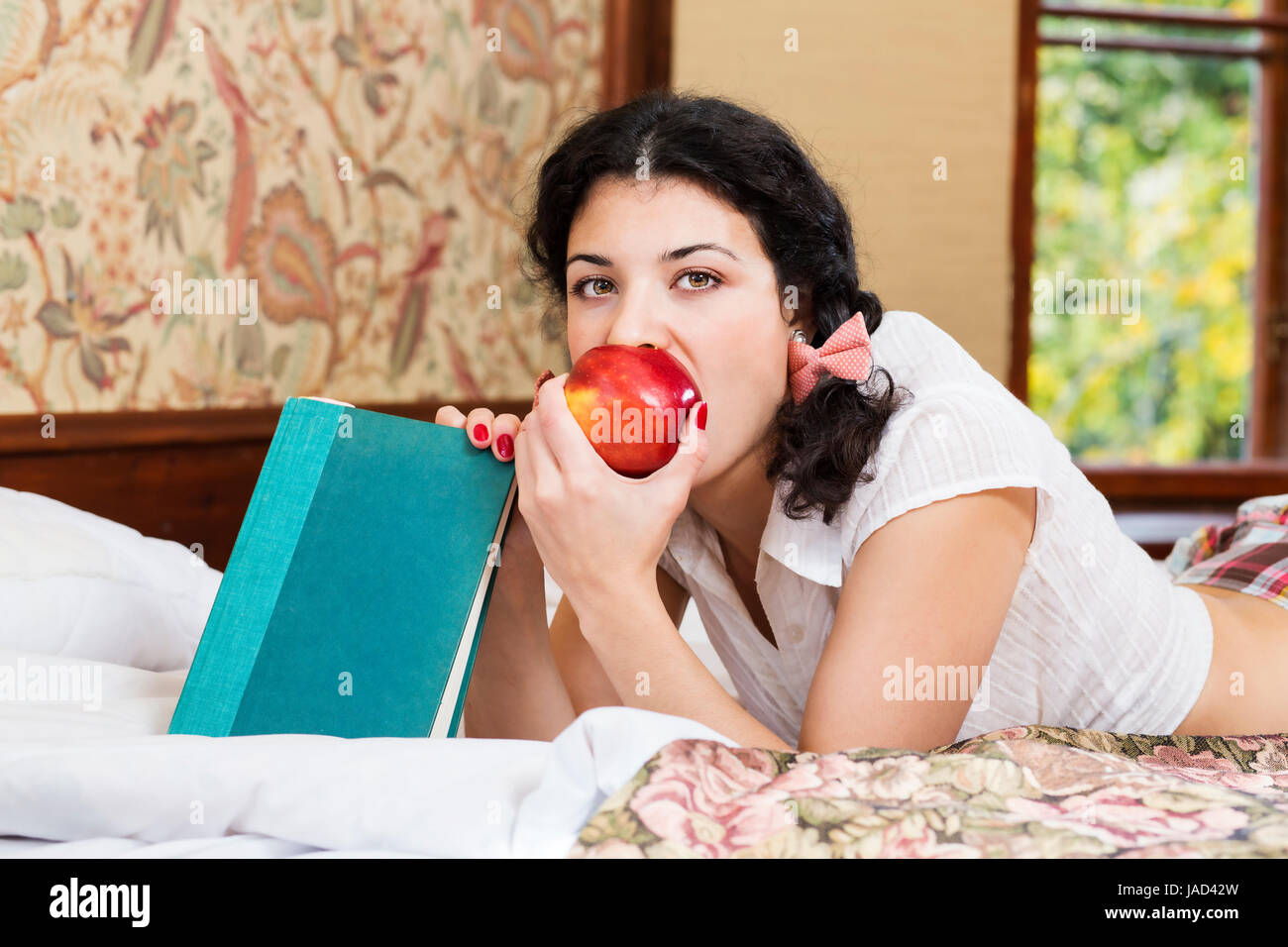 Pretty woman bite red ripe apple at bed Stock Photo - Alamy