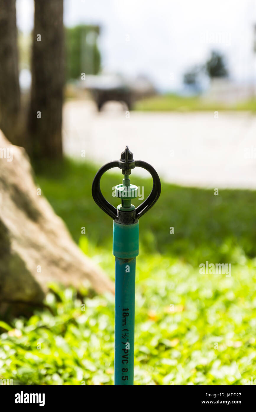 sprinkler water on gardens background Stock Photo - Alamy