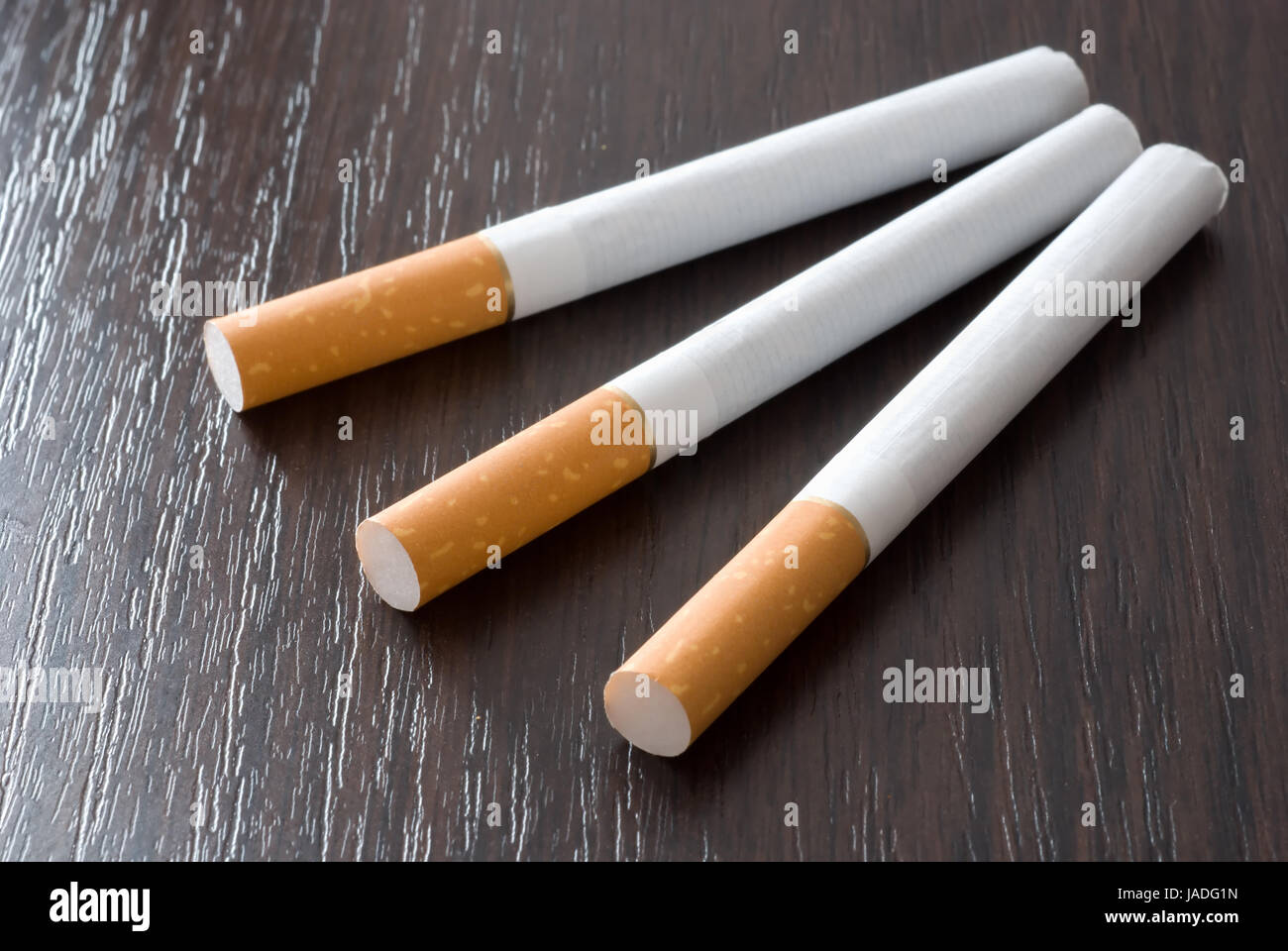 Three cigarettes on the black wooden table Stock Photo - Alamy