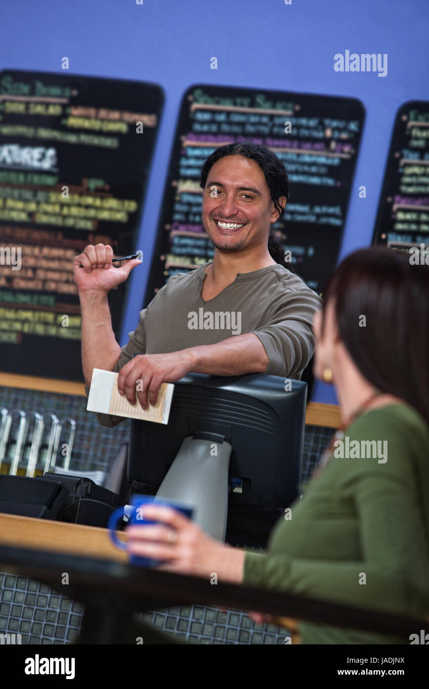 Handsome cafe owner showing menu board to female customer Stock Photo ...