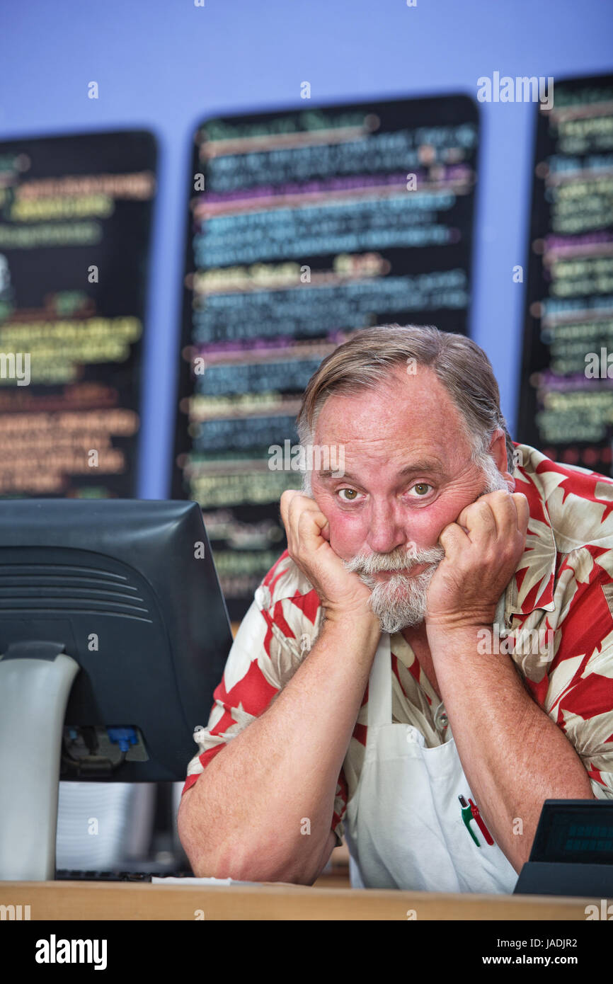 Pouting man with apron behind restaurant counter Stock Photo - Alamy