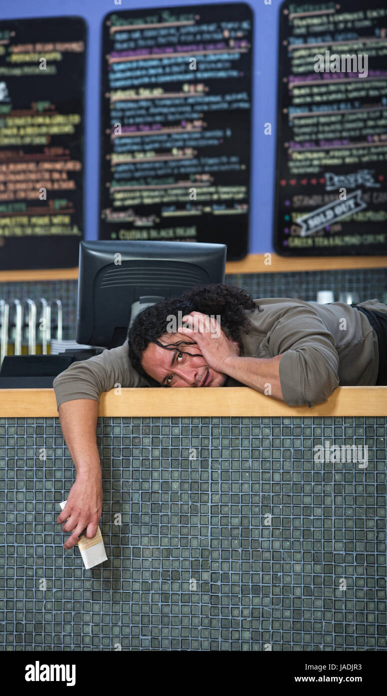 Stressed out worker laying on cafe counter Stock Photo - Alamy