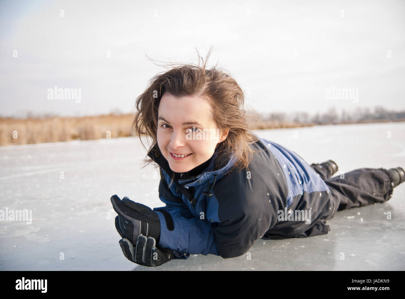 Young smiling woman is lying on ice (frozen lake) - winter outdoor ...