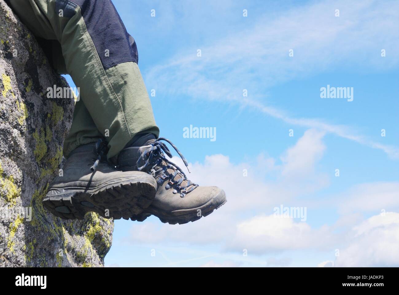 Legs of hiker hang from rock when relaxing with blue sky Stock Photo ...