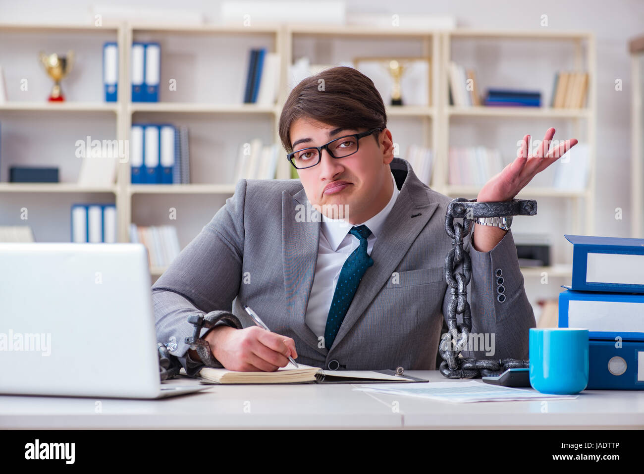 Businessman tied with chains to his work Stock Photo - Alamy