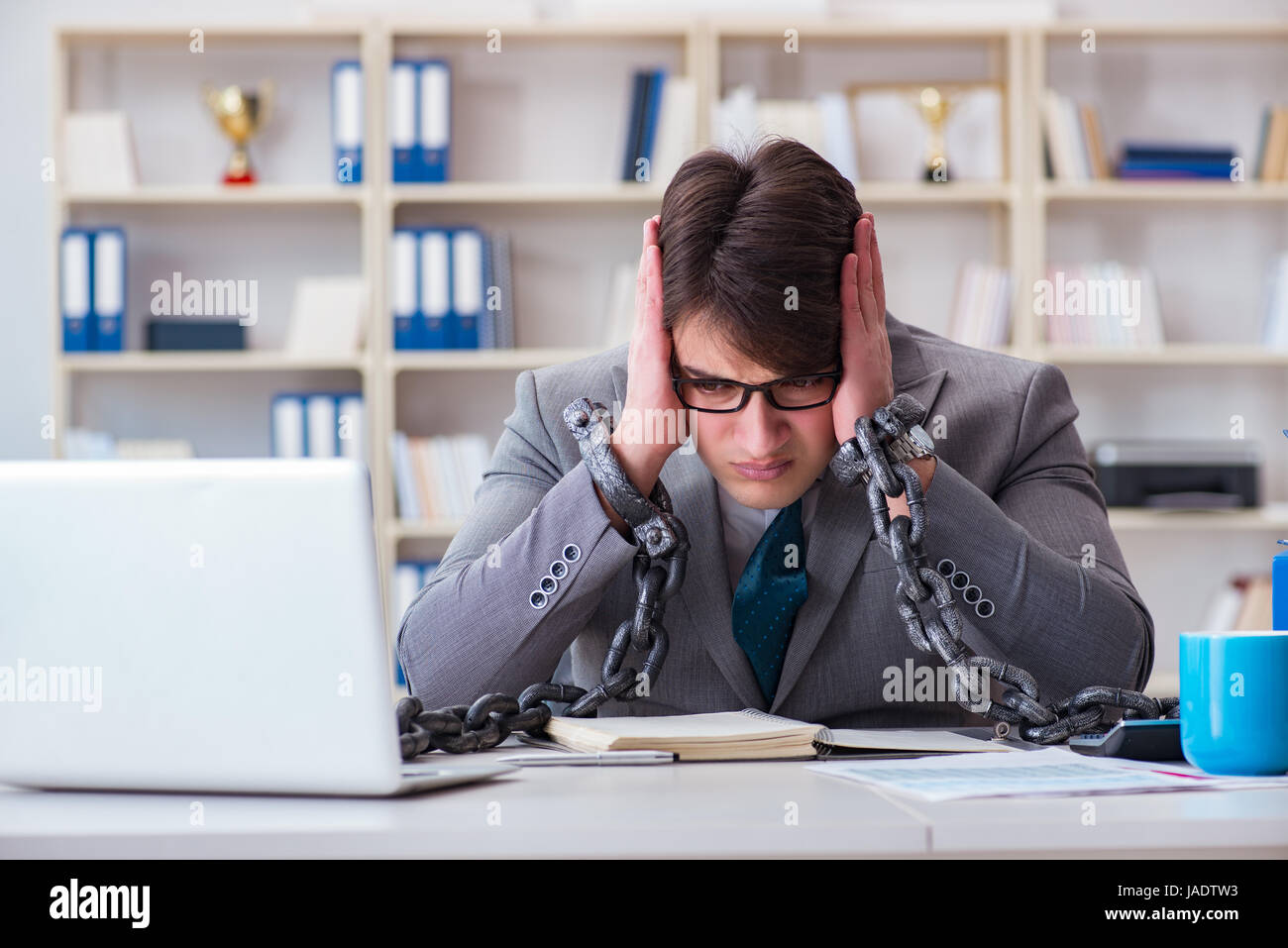 Businessman tied with chains to his work Stock Photo - Alamy