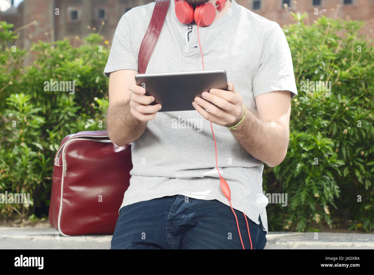 Attractive young man using tablet with headphones. Outdoors Stock Photo ...