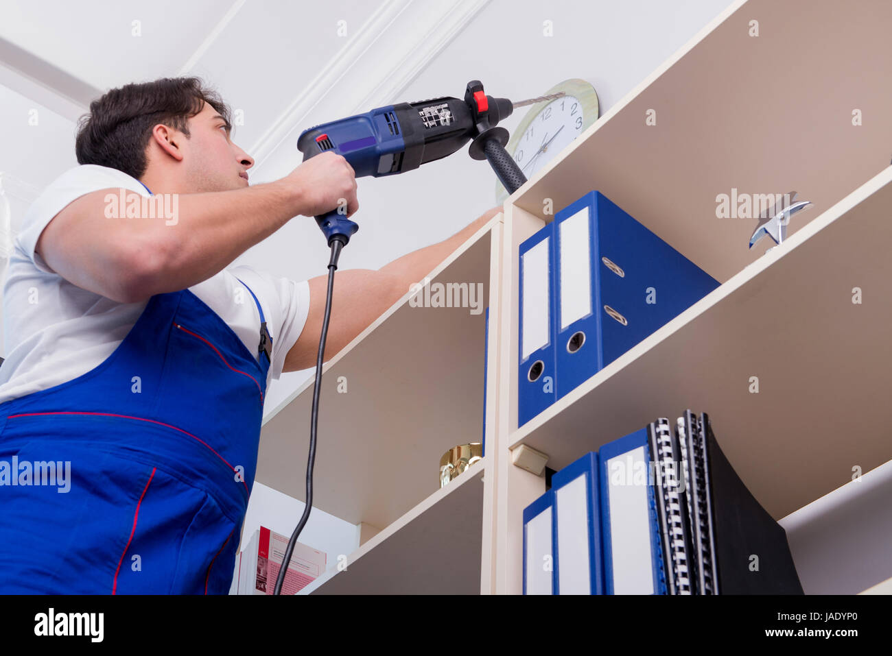 Young worker repairing shelves in office Stock Photo - Alamy