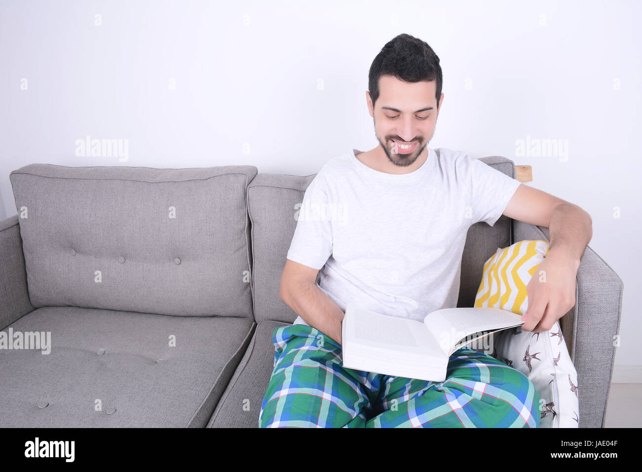 Attractive young man relaxed and reading a book. Indoors Stock Photo ...