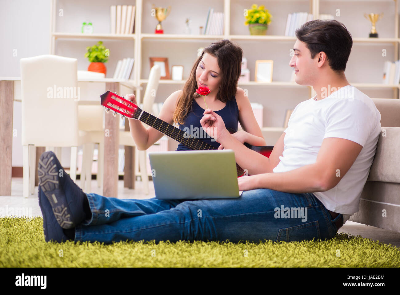 Romantic pair playing guitar on floor Stock Photo - Alamy