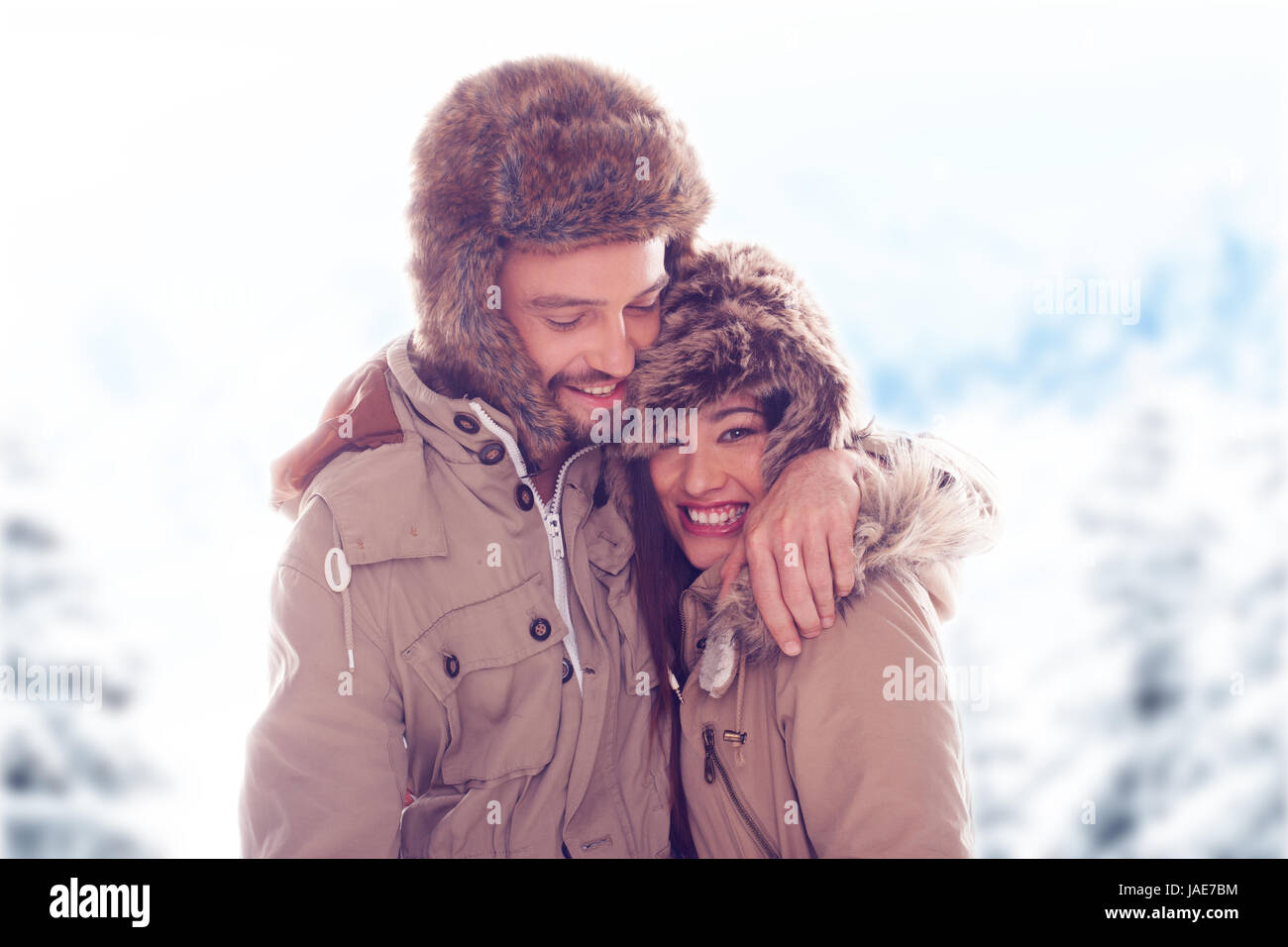 Loving couple cuddling outdoors in a snow landscape wearing heavy ...