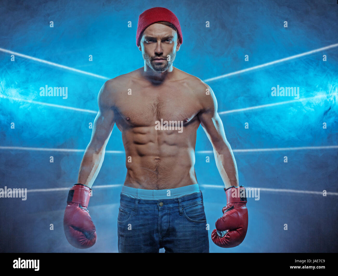 Young athletic boxer exhibiting his six-pack abdominals wearing gloves ...