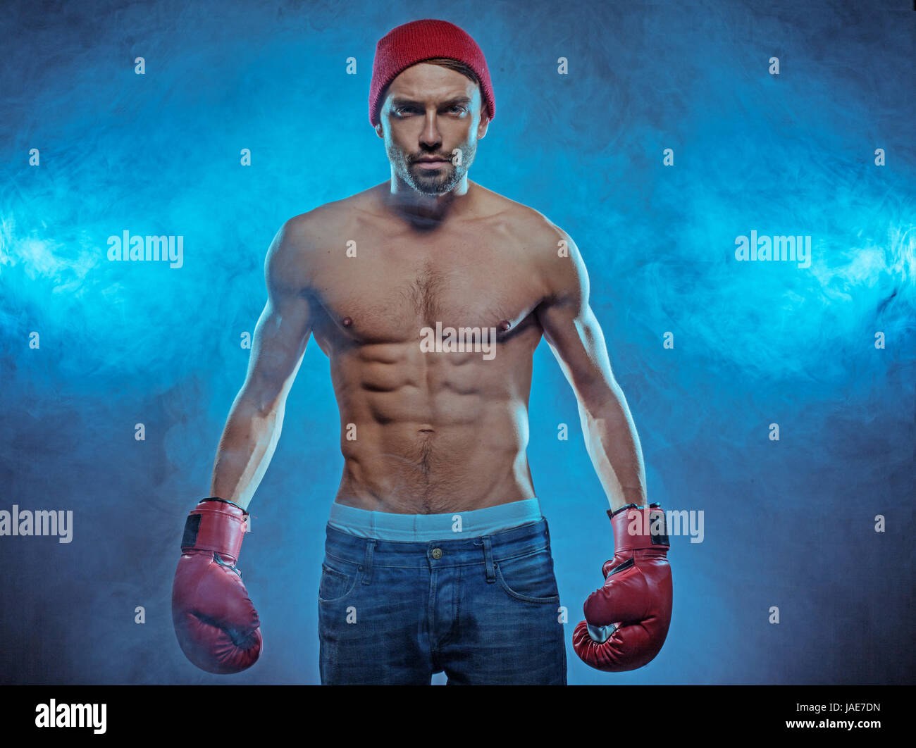 Young athletic boxer exhibiting his six-pack abdominals wearing gloves ...