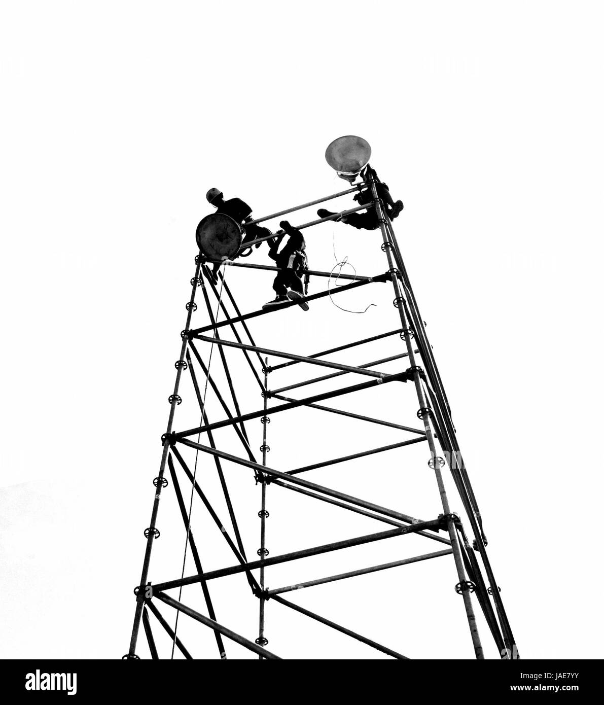 Workers set up powerful lights on scaffolds, seen in silhouette Stock ...